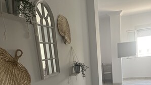 Quarto com uma grande janela em arco, uma cesta de palha e uma planta em vaso na parede.
