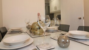 Uma mesa de jantar posta com pratos, copos e uma tigela decorativa.