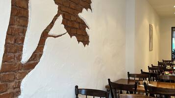 Interior de restaurante com paredes de tijolos aparentes, mesas e cadeiras de madeira.