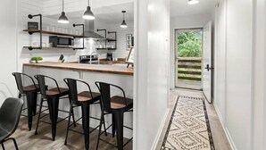 Uma cozinha moderna com banquetas, micro-ondas e iluminação pendente.