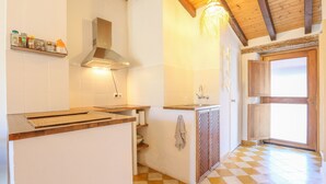 Uma cozinha com ilha central, fogão embutido e luminária pendente.