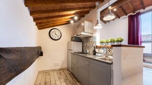 Cozinha com vigas de madeira, relógio, armários, micro-ondas e janela com vista.