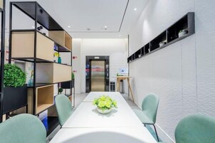 Uma sala de conferências moderna com uma mesa comprida, cadeiras e uma estante.