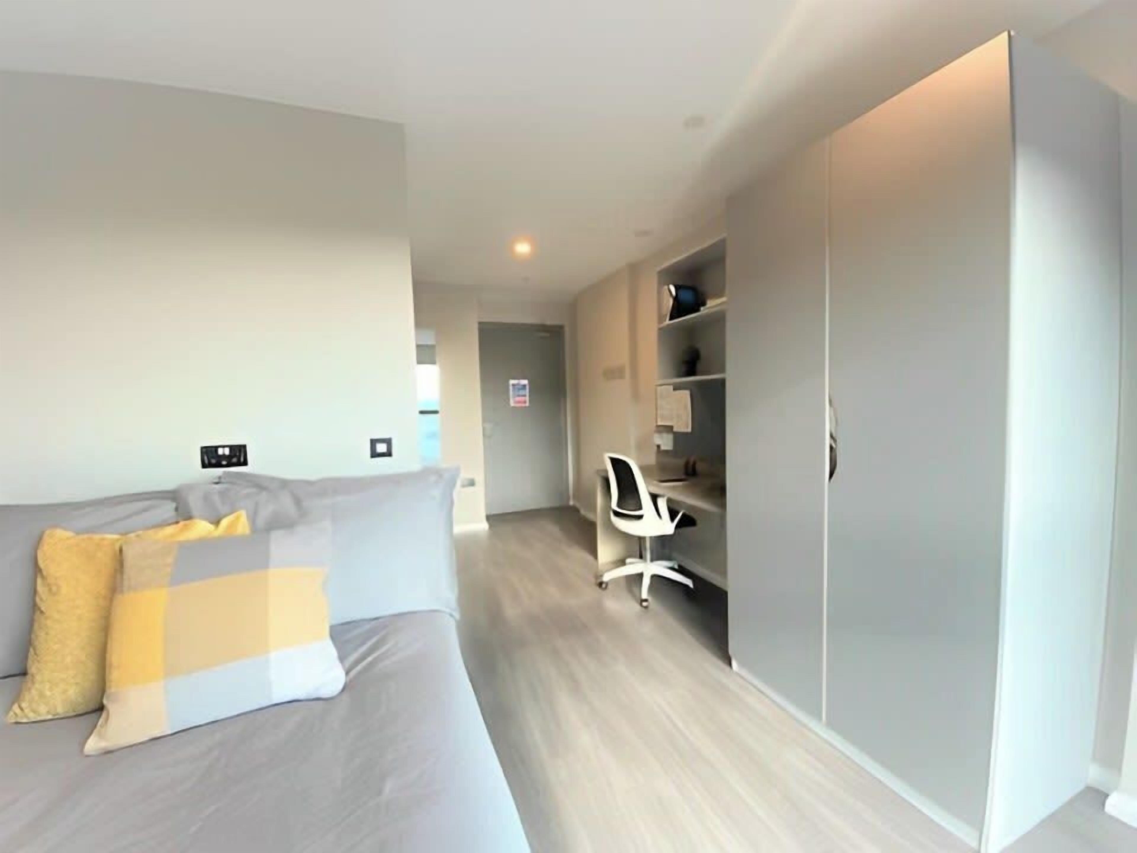 Um quarto moderno com uma cama, uma escrivaninha e um guarda-roupa.