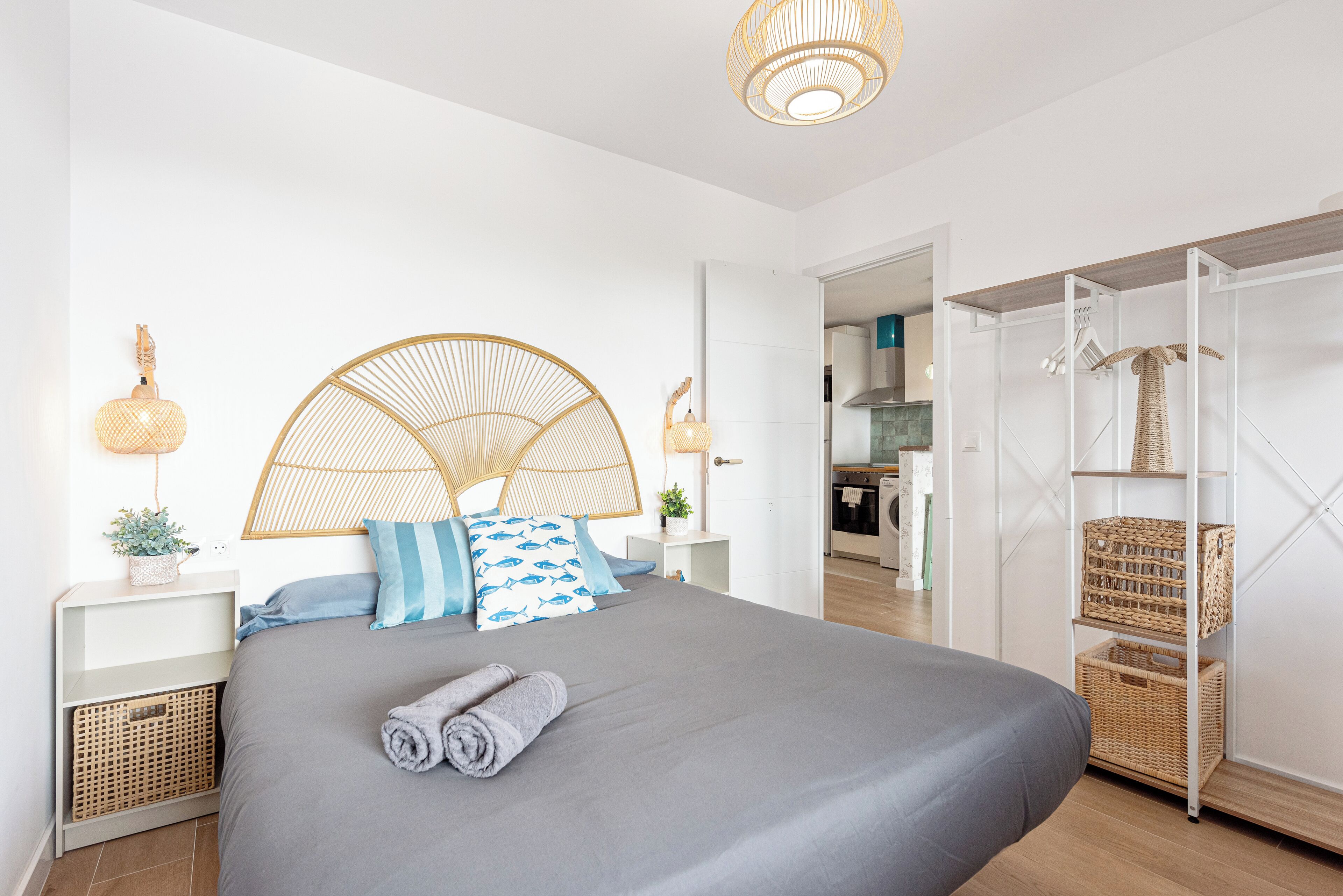 Quarto moderno com cama grande, cabeceira de madeira, luminárias laterais e guarda-roupa embutido.