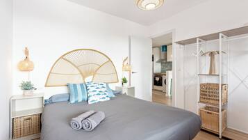 Quarto moderno com cama grande, cabeceira de madeira, luminárias laterais e guarda-roupa embutido.