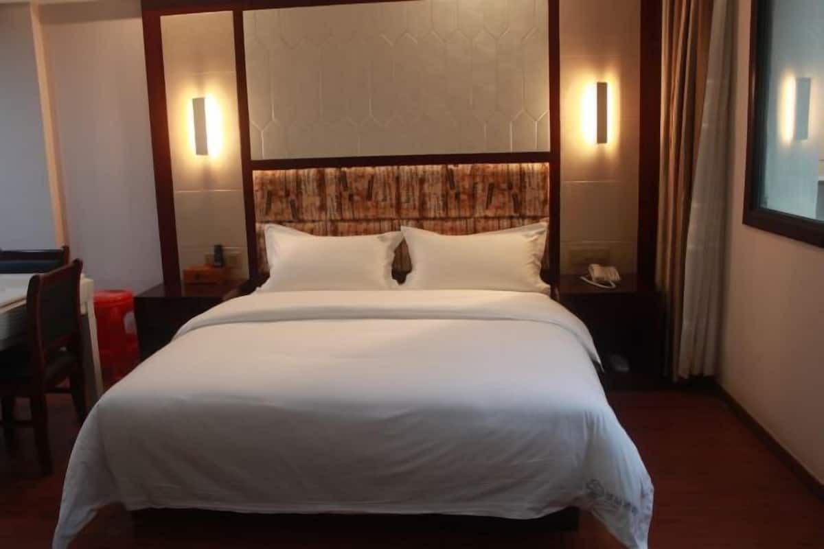 Quarto de hotel com uma cama grande, uma escrivaninha e uma cadeira.