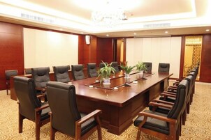 Uma sala de conferência com uma mesa comprida, várias cadeiras e um lustre.