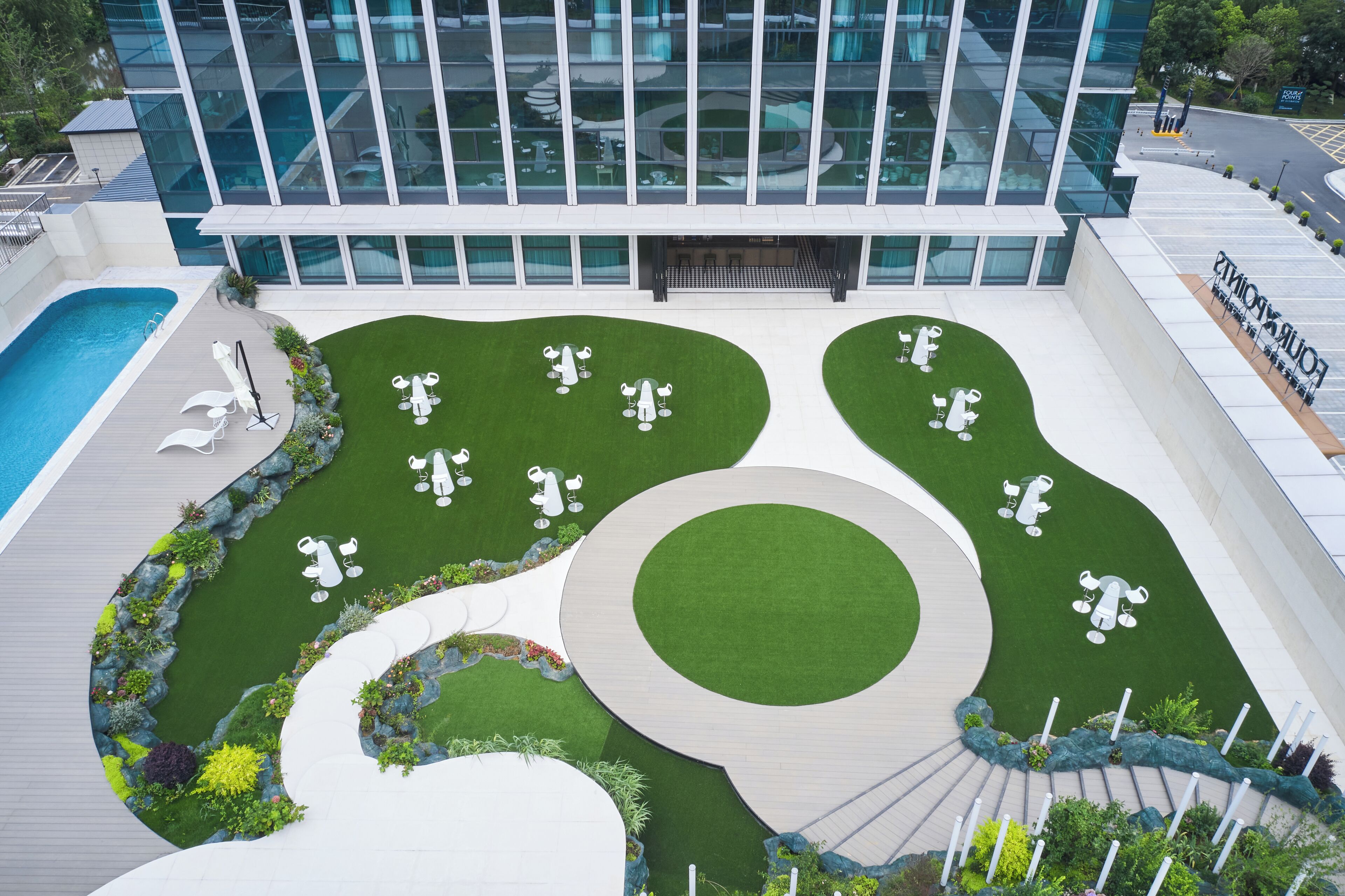 Um hotel moderno com piscina no terraço, áreas de estar ao ar livre e um jardim ajardinado.