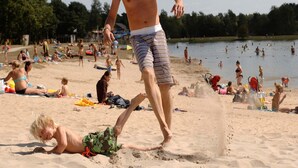 Praia lotada com pessoas se bronzeando e nadando.