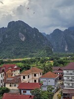 Área residencial com casas de telhados vermelhos, cercada por vegetação exuberante e montanhas ao fundo.
