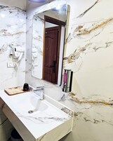 Casa de banho com lavatório de mármore, secador de cabelo e espelho.