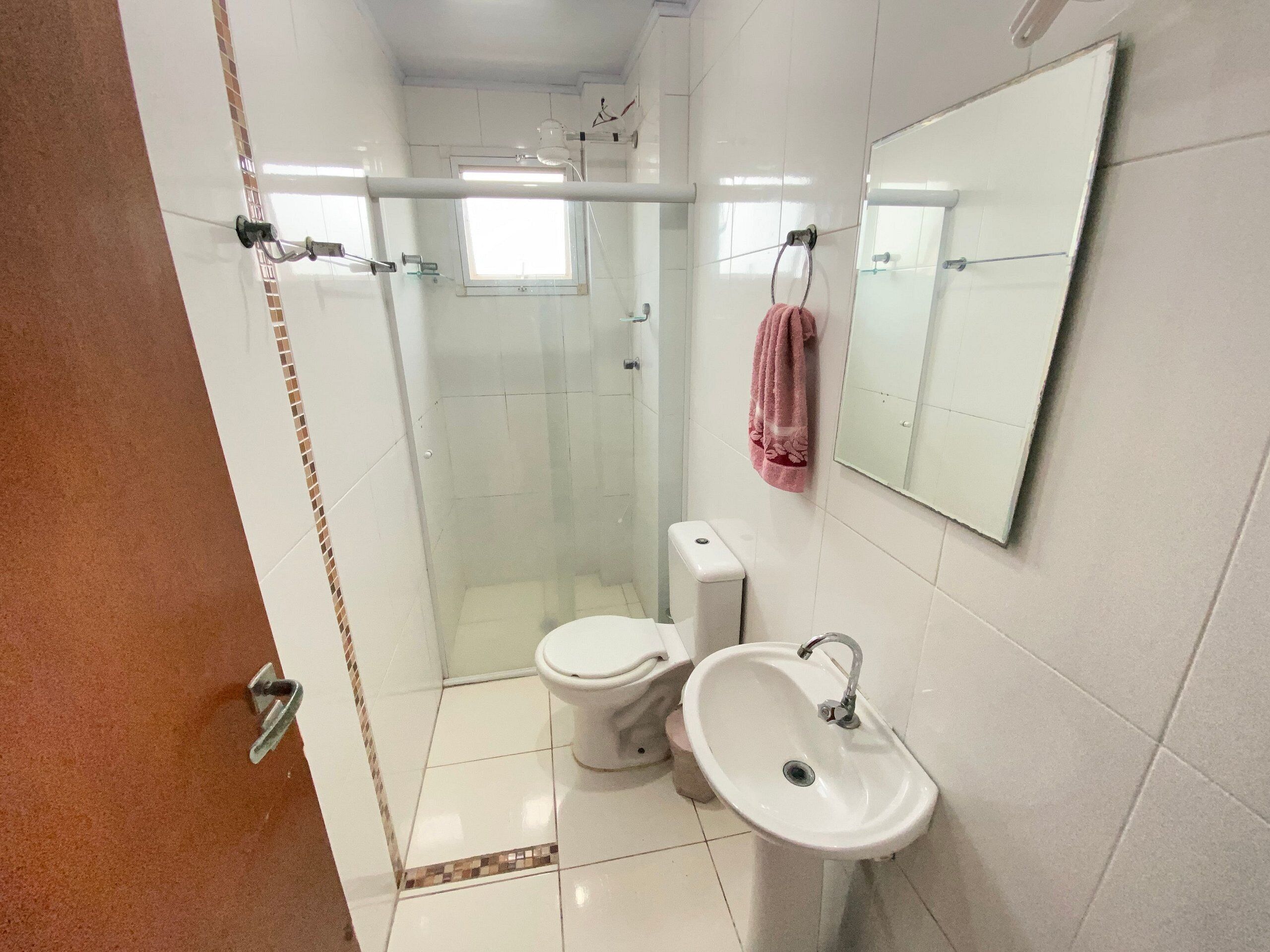 Casa de banho moderna com cabine de chuveiro em vidro, sanita e lavatório.
