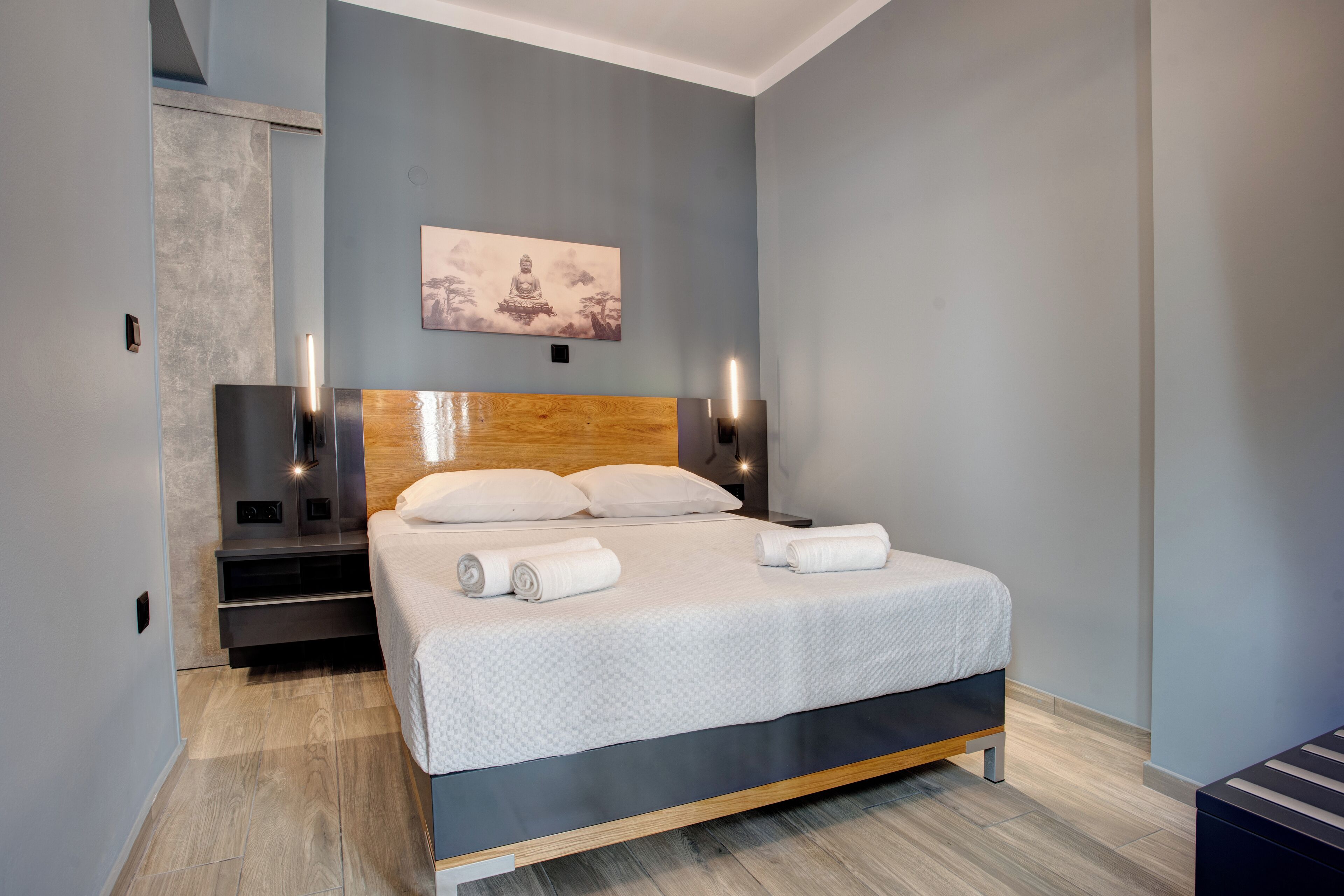 Um quarto moderno com uma cama grande, mesas de cabeceira, uma obra de arte na parede e uma cabeceira de madeira.