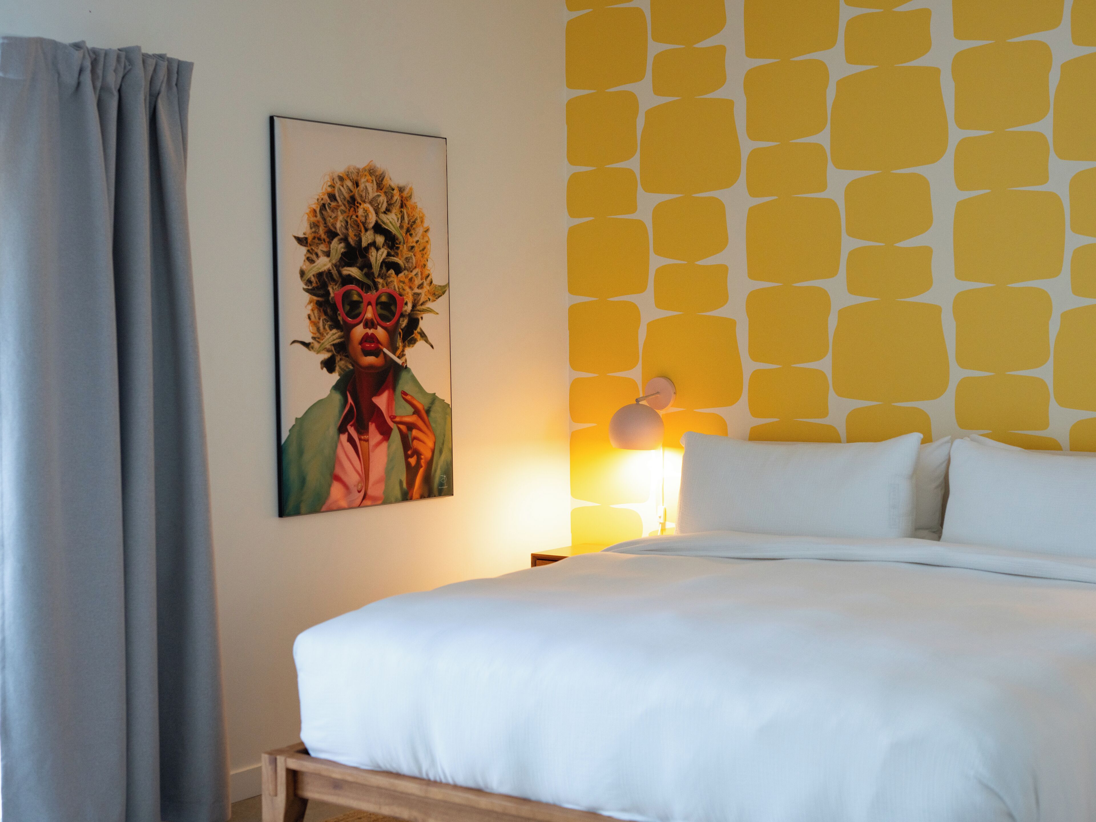 Quarto de hotel com uma cama, um quadro na parede e um papel de parede estampado.