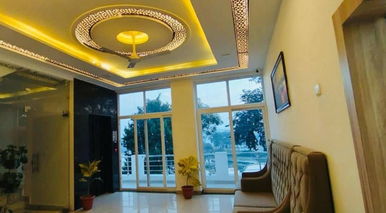 Um quarto espaçoso com uma janela grande, um candeeiro no teto e um sofá.