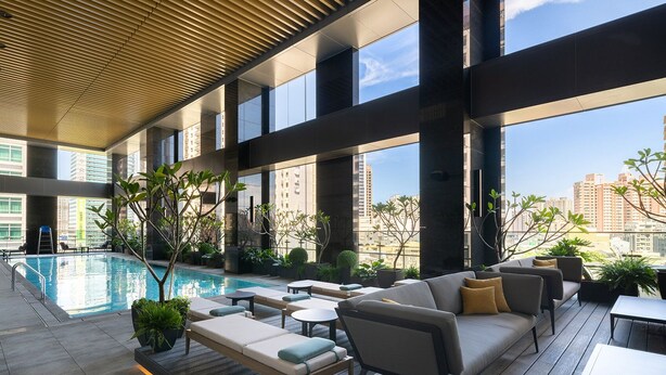 Uma área interna de piscina moderna, com cadeiras de descanso e vista para a cidade.