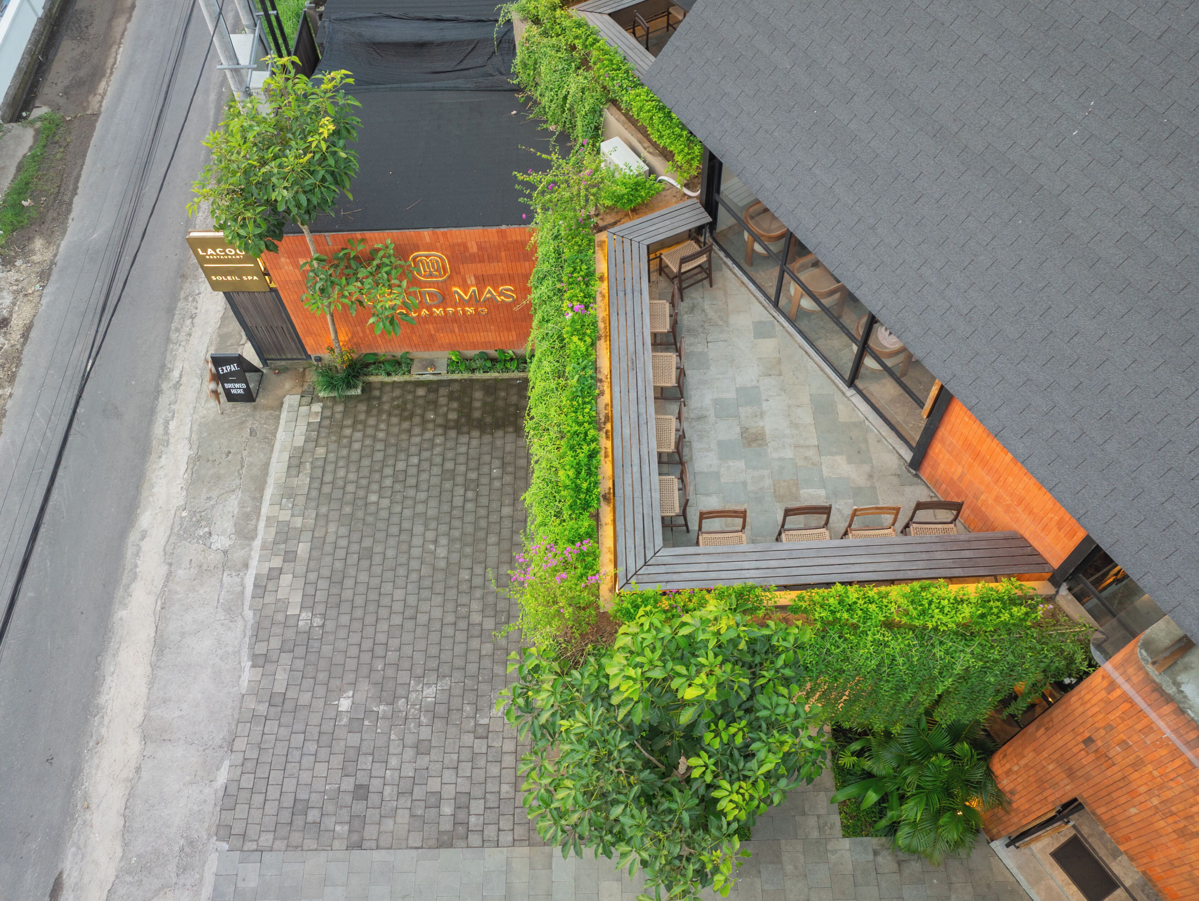 Terraço no telhado com área de estar, um caminho pavimentado e um edifício com a placa 'LACOMBE SPA'.