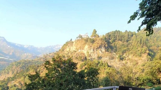 Varanda com duas cadeiras de plástico e vista para uma paisagem montanhosa.