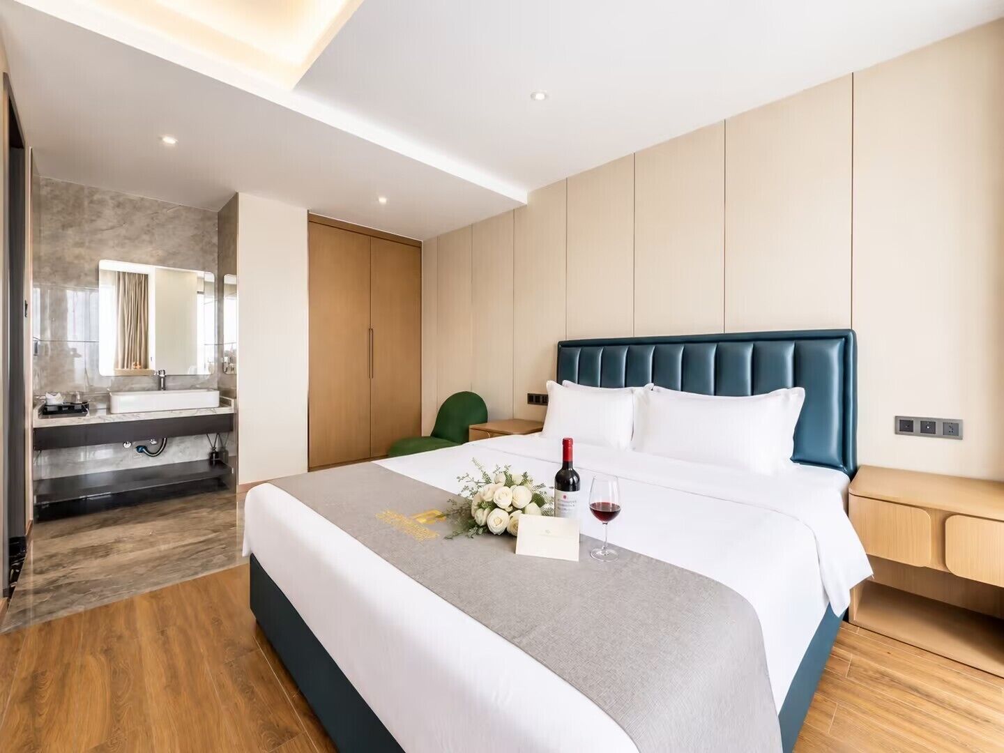 Quarto de hotel moderno com cama, mesa de cabeceira e banheiro com toucador.