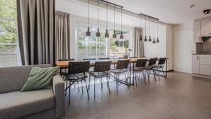 Uma sala de estar moderna com área de jantar, janelas amplas e cozinha.