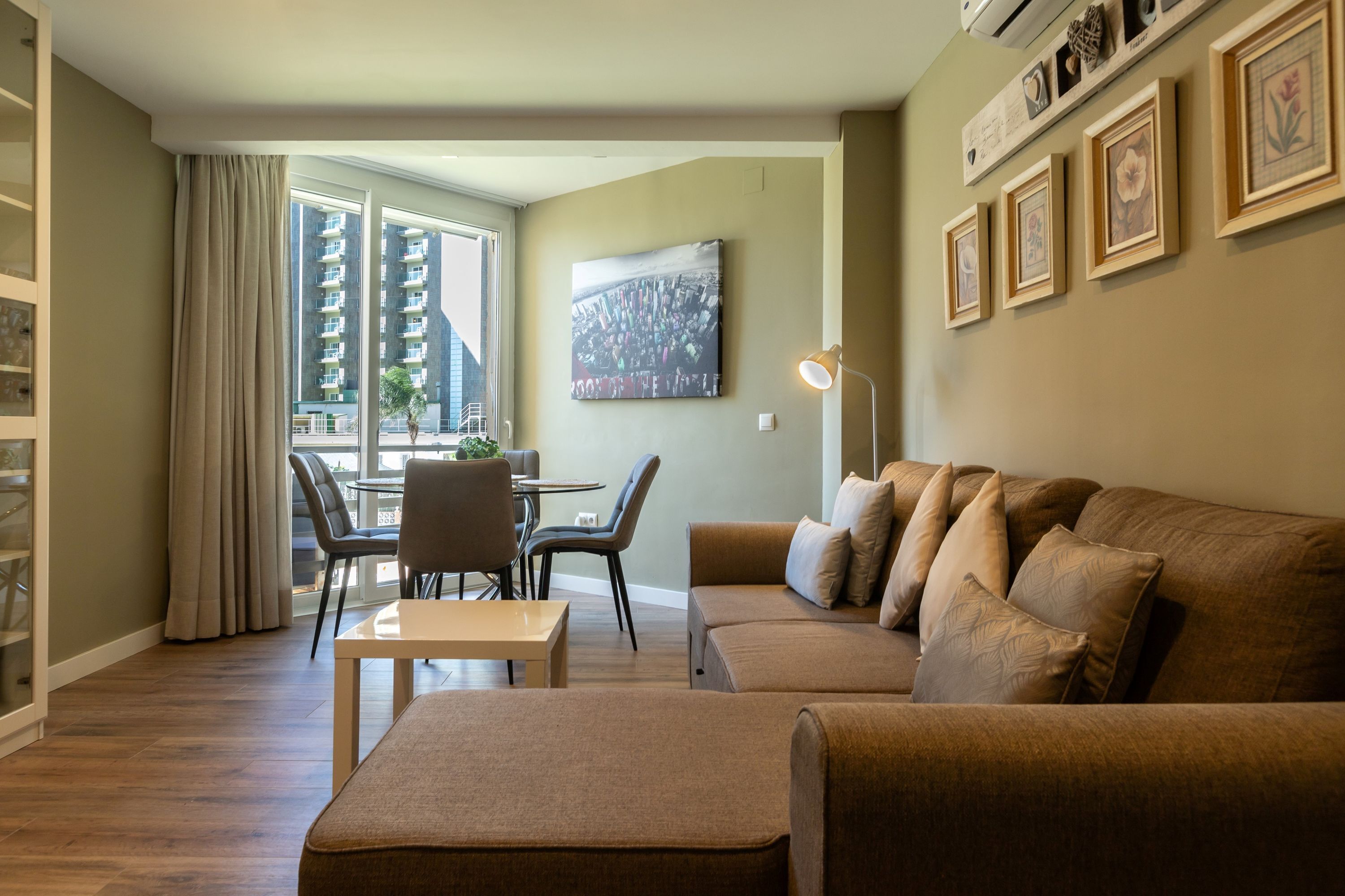Uma sala de estar moderna com sofá, apoio de pés e mesa de jantar.