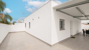 Uma área externa espaçosa e moderna, com telhado plano, varanda coberta e vista para o céu.