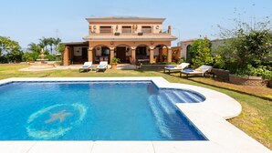 Uma casa grande com piscina, área de estar externa e um jardim bem cuidado.
