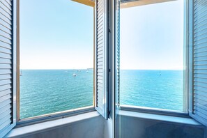 Uma janela com vista para o mar e barcos.