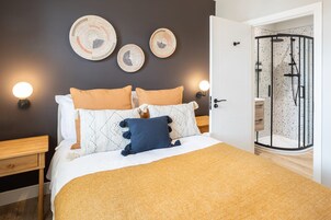 Quarto com cama, mesas de cabeceira e área de chuveiro.
