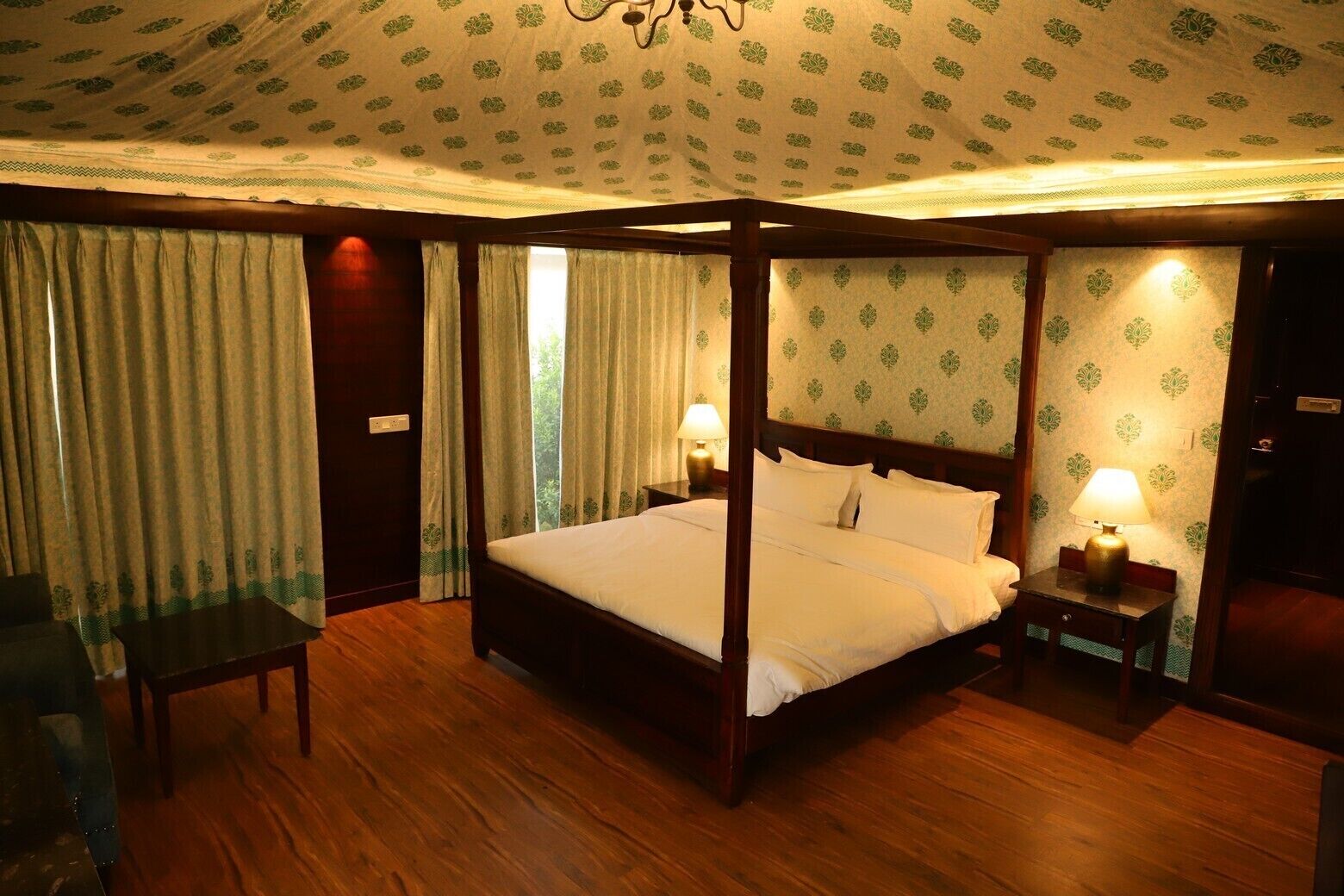 Uma cama de dossel com lençóis brancos, cabeceira de madeira e mesas de cabeceira com abajures.