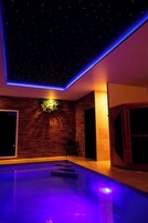 Um interior moderno com teto estrelado, piscina e paredes de madeira.