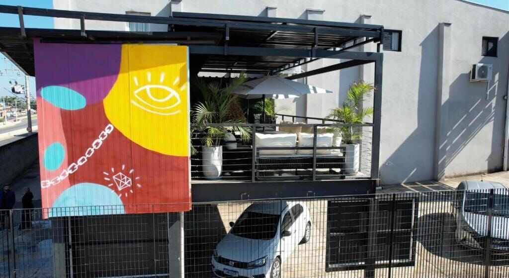Um edifício com área de estar coberta ao ar livre, estacionamento e uma faixa colorida.