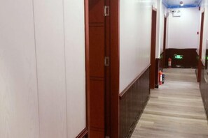 Um corredor com portas de madeira, um extintor e um alarme de incêndio na parede.