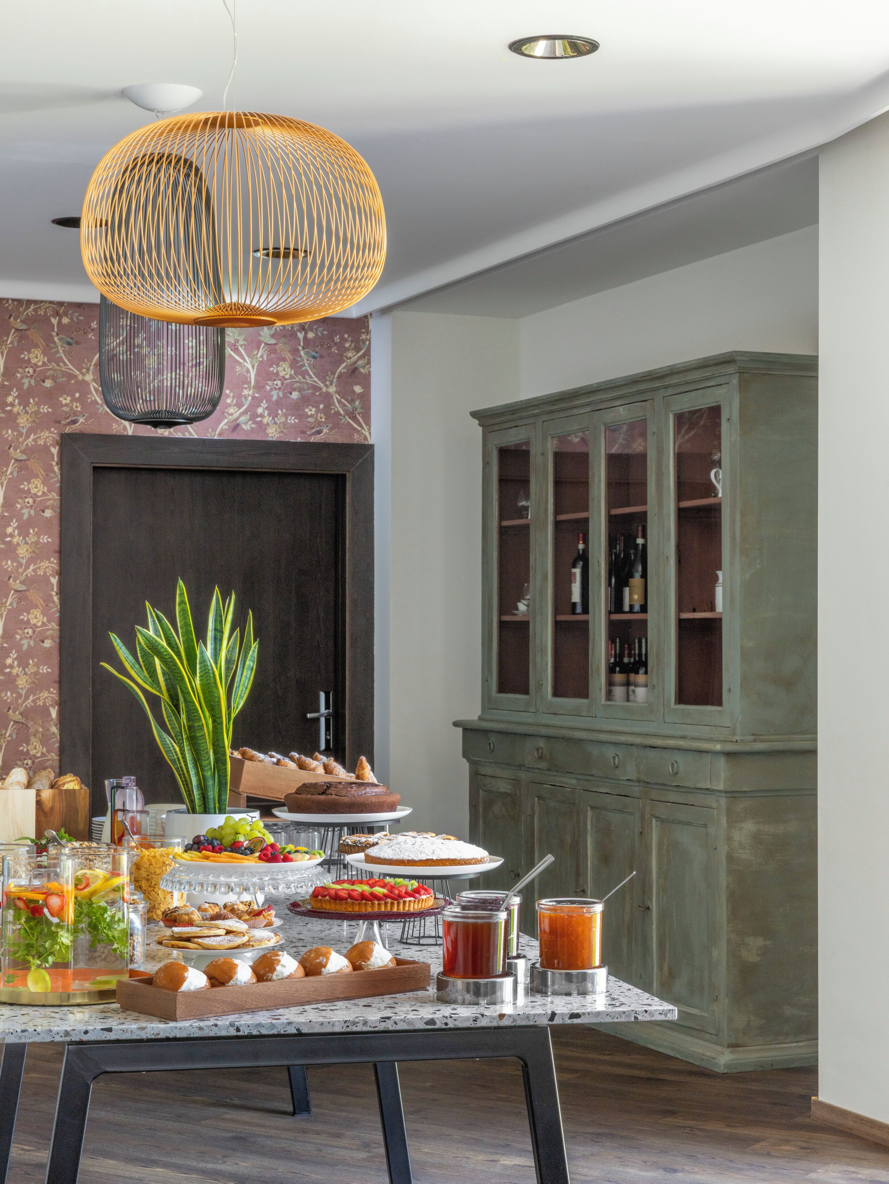 Uma área de refeições com mesa posta, um armário com portas de vidro e um lustre.