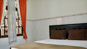 Cama bem arrumada com manta marrom, cabeceira e duas almofadas marrons.
