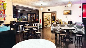 Um restaurante com área de bar, diversas opções de assento e cozinha à vista.