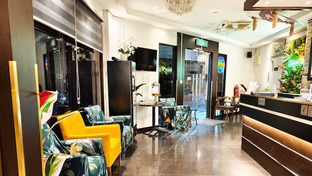 Um saguão de hotel com balcão de recepção, área de estar com cadeiras estampadas e um lustre moderno.