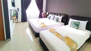 Quarto de hotel com duas camas, uma janela grande com cortinas, uma televisão de tela plana e uma pequena planta numa prateleira.