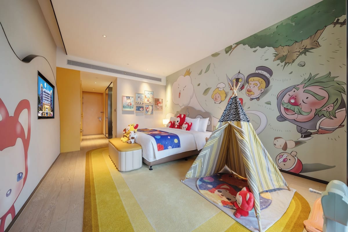 Quarto infantil com cama, tenda de brincar e um mural na parede.