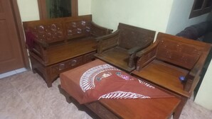 Um conjunto de sofá de madeira com um banquinho combinando, uma mesinha e uma almofada decorativa.