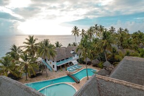 Um resort com piscina, palmeiras e vista para o mar.
