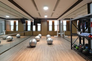 Uma academia com bolas de exercício, suporte para pesos e um espelho grande.