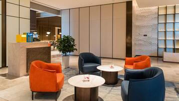 Um lobby moderno com assentos, balcão de recepção e um painel decorativo.