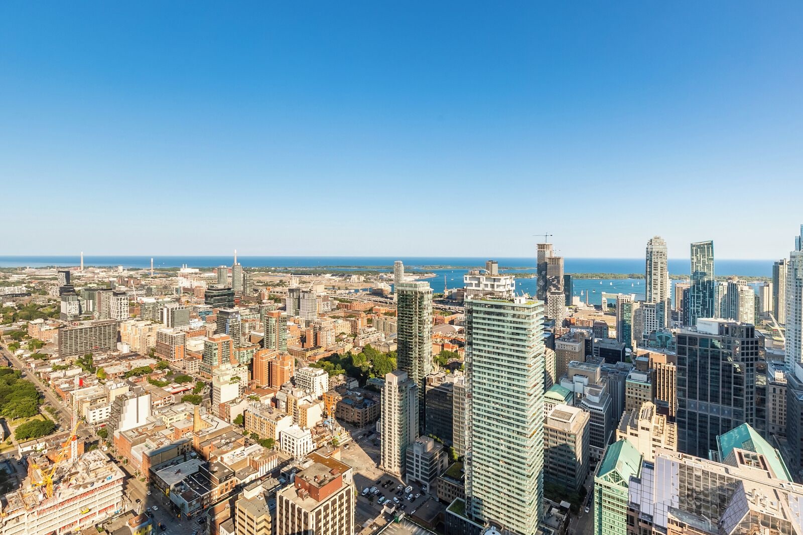 Céu claro sobre paisagem urbana com arranha-céus e arquitetura moderna, com um corpo de água ao longe.