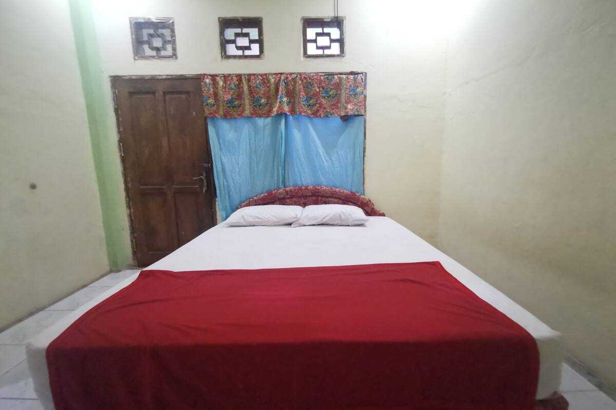 Um quarto com cama, porta de madeira e cortina azul.