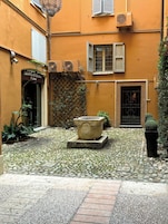 Um pátio com piso de pedras, um vaso de pedra e um edifício com a placa "Galleria Antica Aquaria".