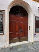 Uma porta dupla de madeira grande com puxador de metal e um painel de vidro acima.
