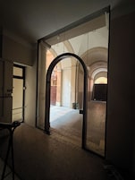Um corredor interno com uma porta de vidro que dá para um pátio.