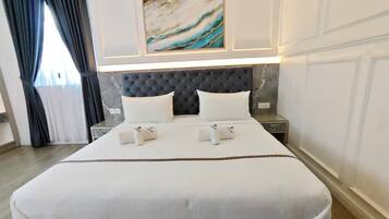 Uma cama bem arrumada com cabeceira estofada, roupa de cama branca e duas almofadas.